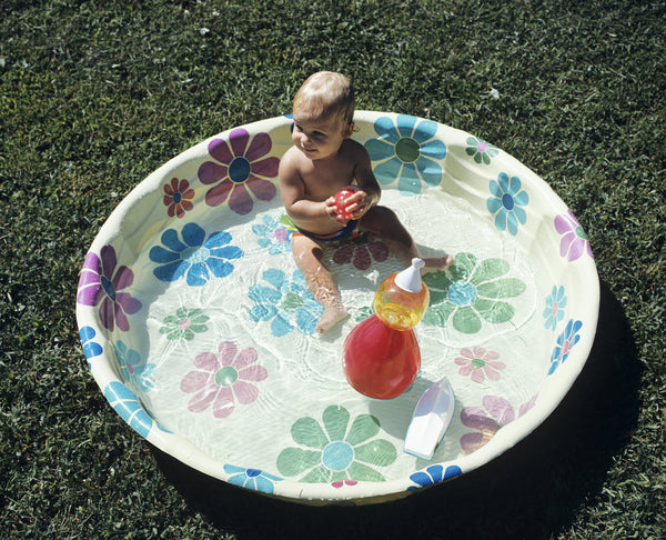 1970s baby sitting in plastic backyard kiddy pool viewed from above ...